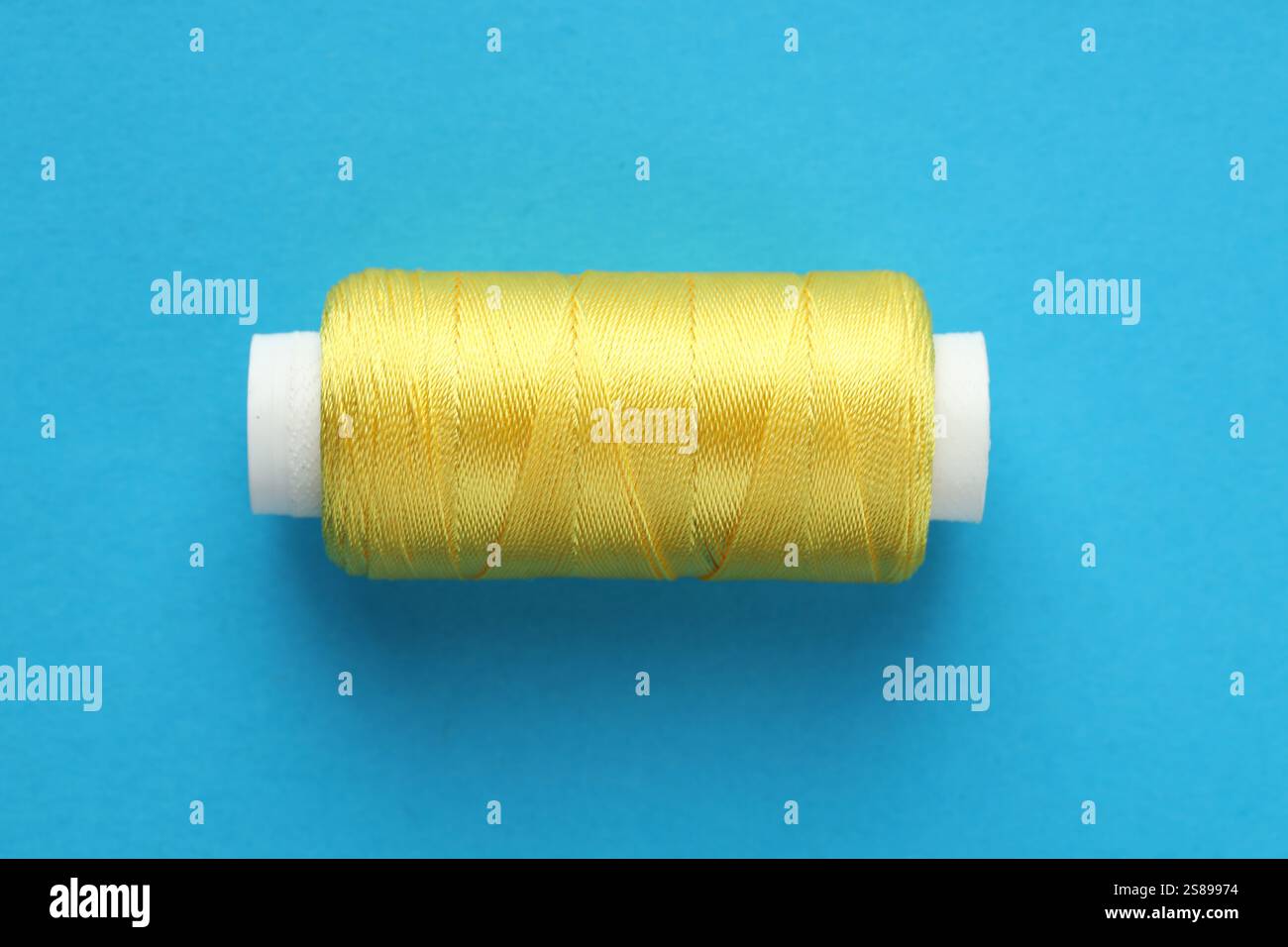 Spool of yellow sewing thread on light blue background, top view Stock ...