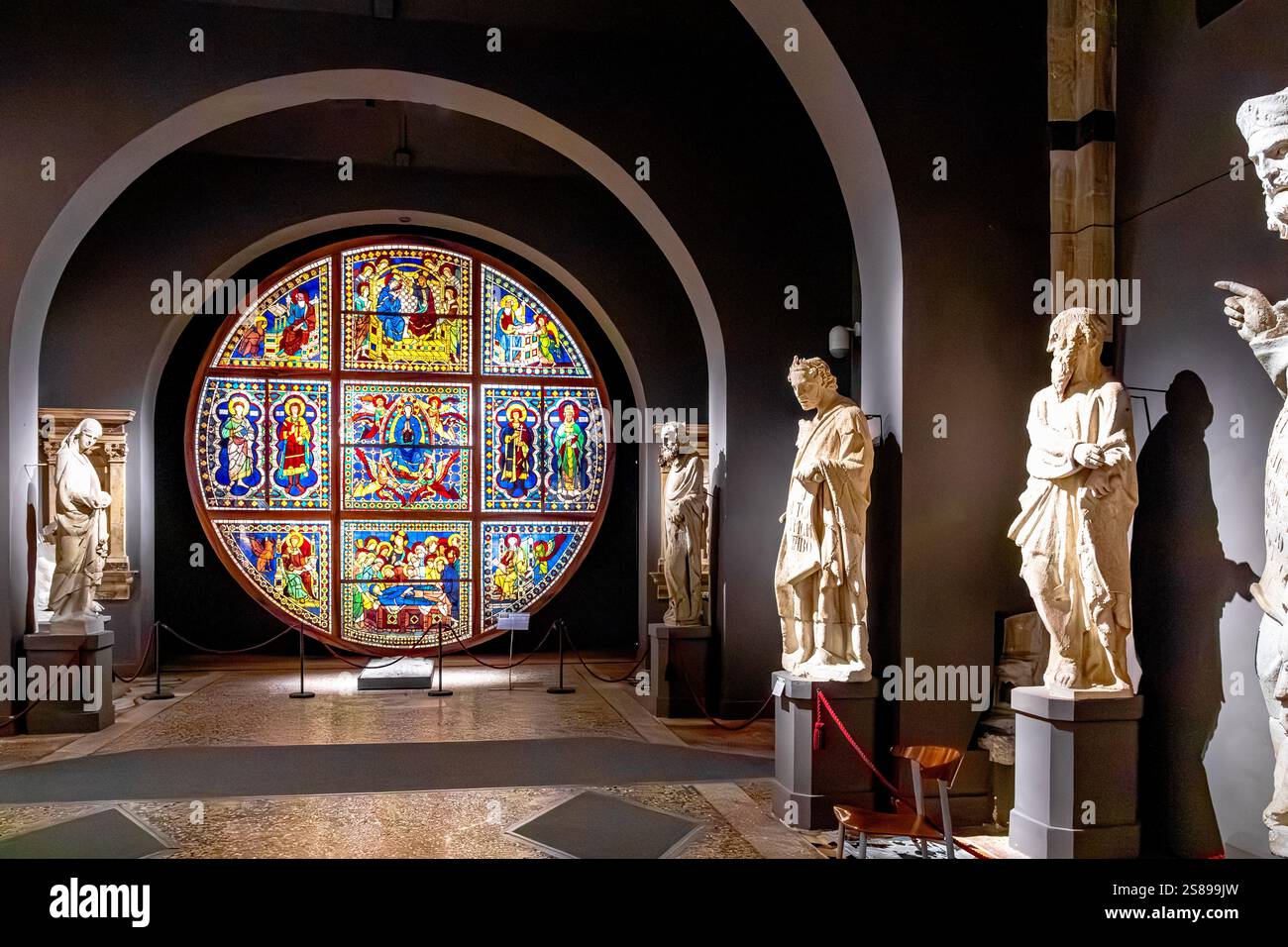 The great stained glass window by Ducco,surrounded by marble statues inside the Museo dell'Opera ...