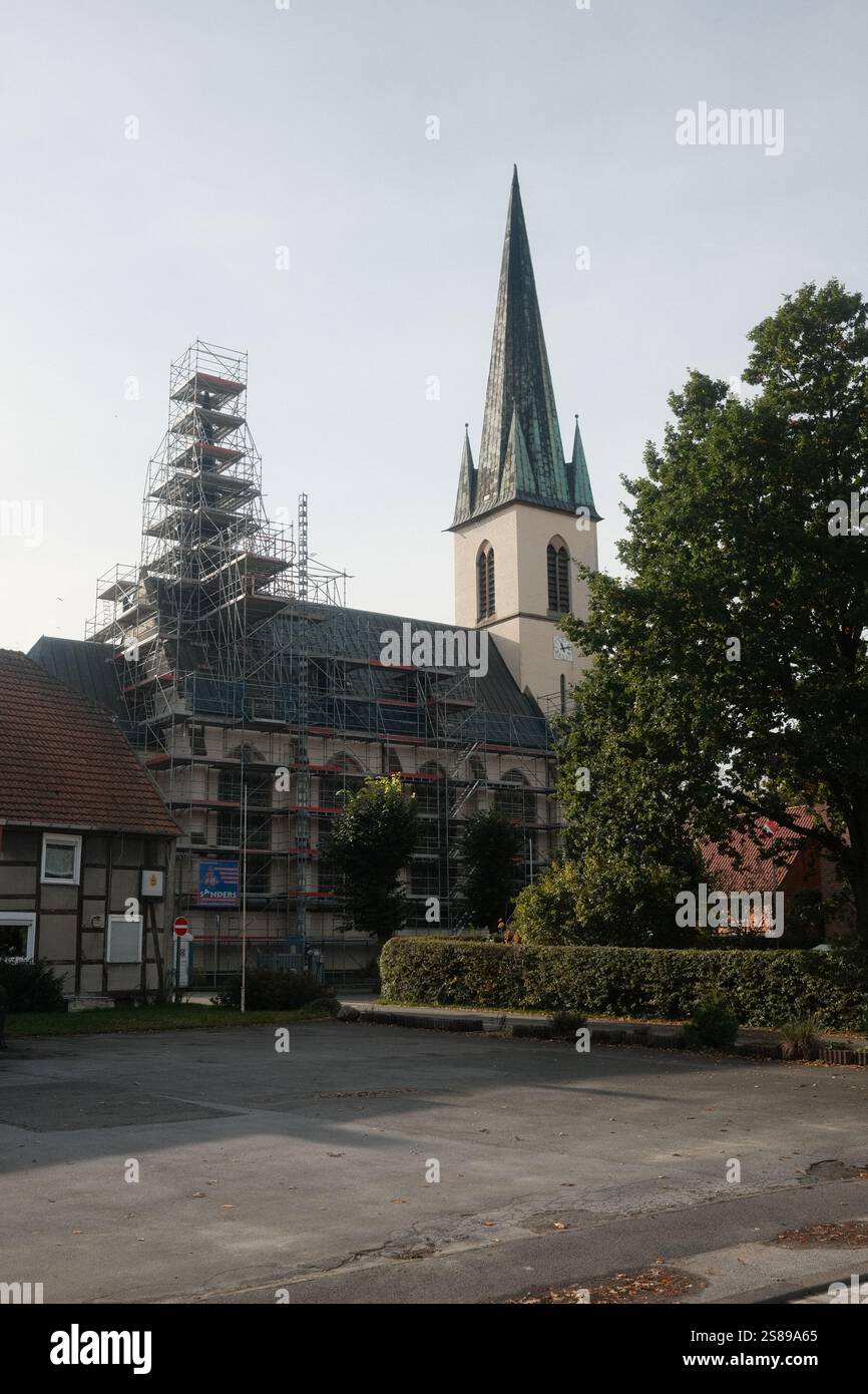 A church with a tall steeple and a small house next to it. The house is ...