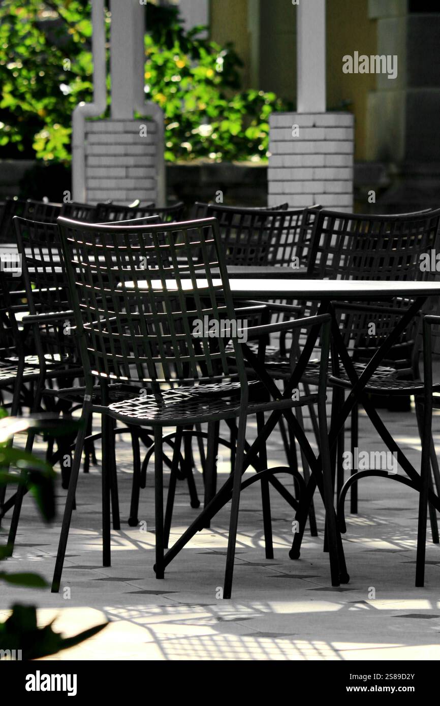 A modern courtyard with cafe tables and chairs in a black and white ...