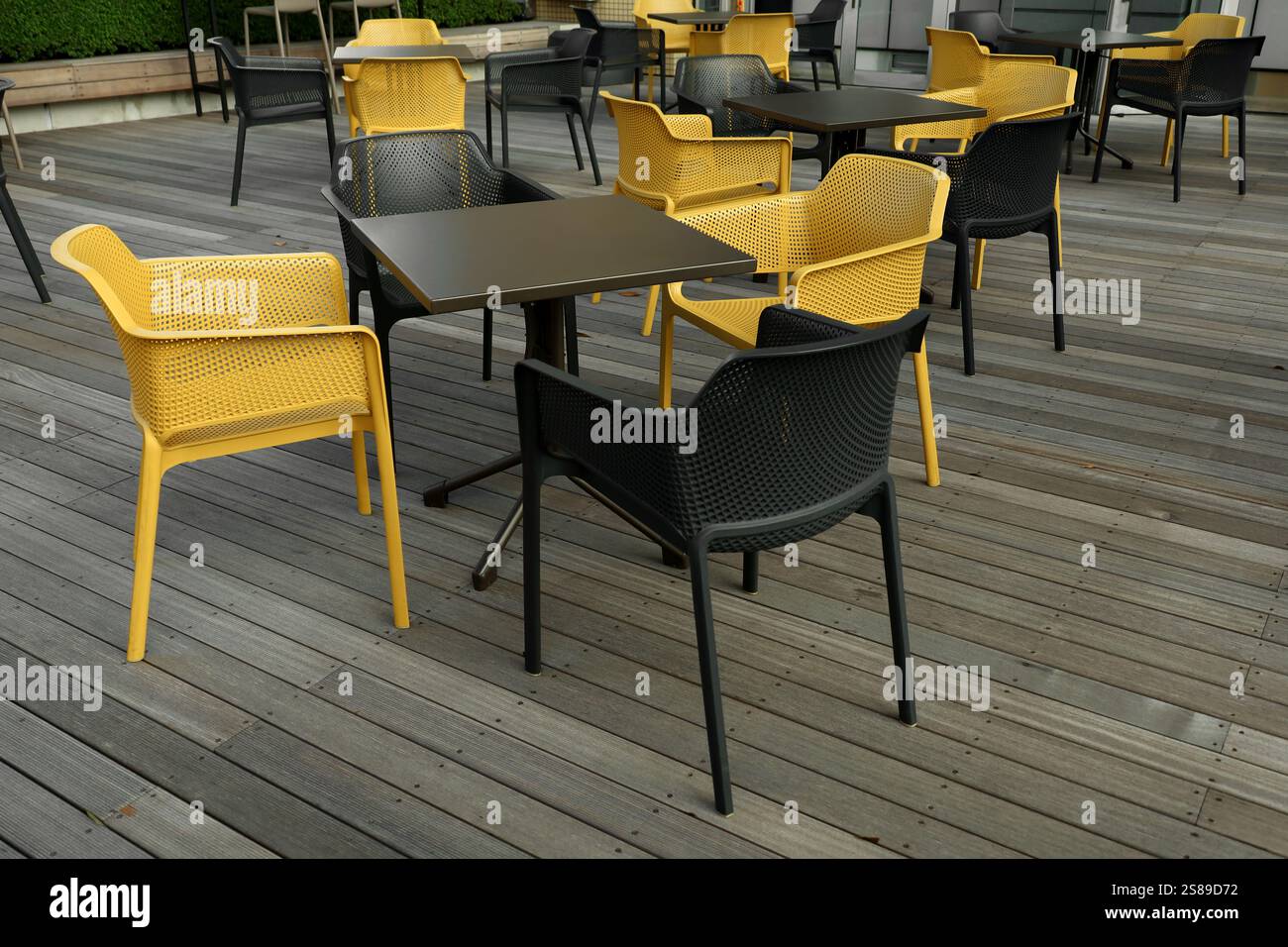 Cafe tables lined up in the wooden deck courtyard Stock Photo - Alamy