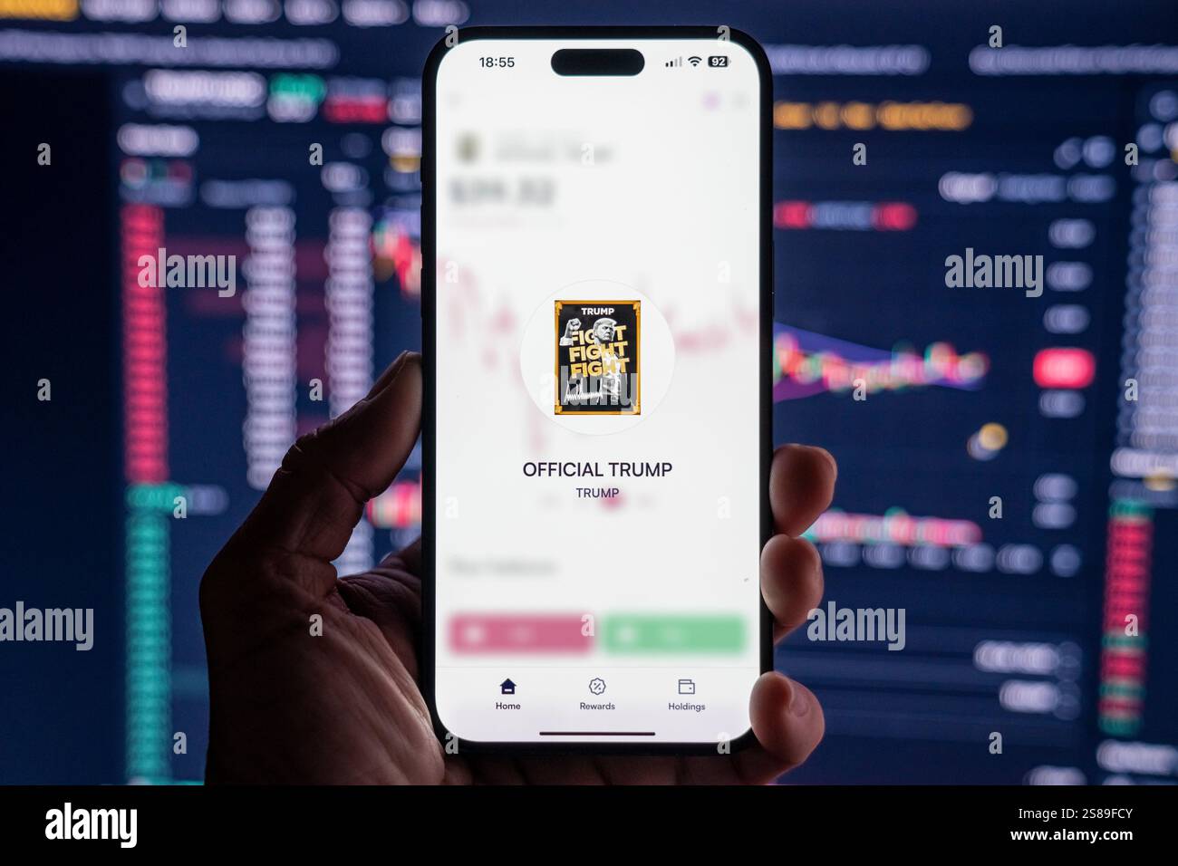 Man holding a phone displaying the OFFICIAL TRUMP meme, with a blurred ...
