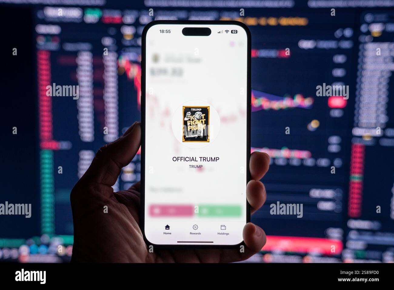 Man holding a phone displaying the OFFICIAL TRUMP meme, with a blurred ...