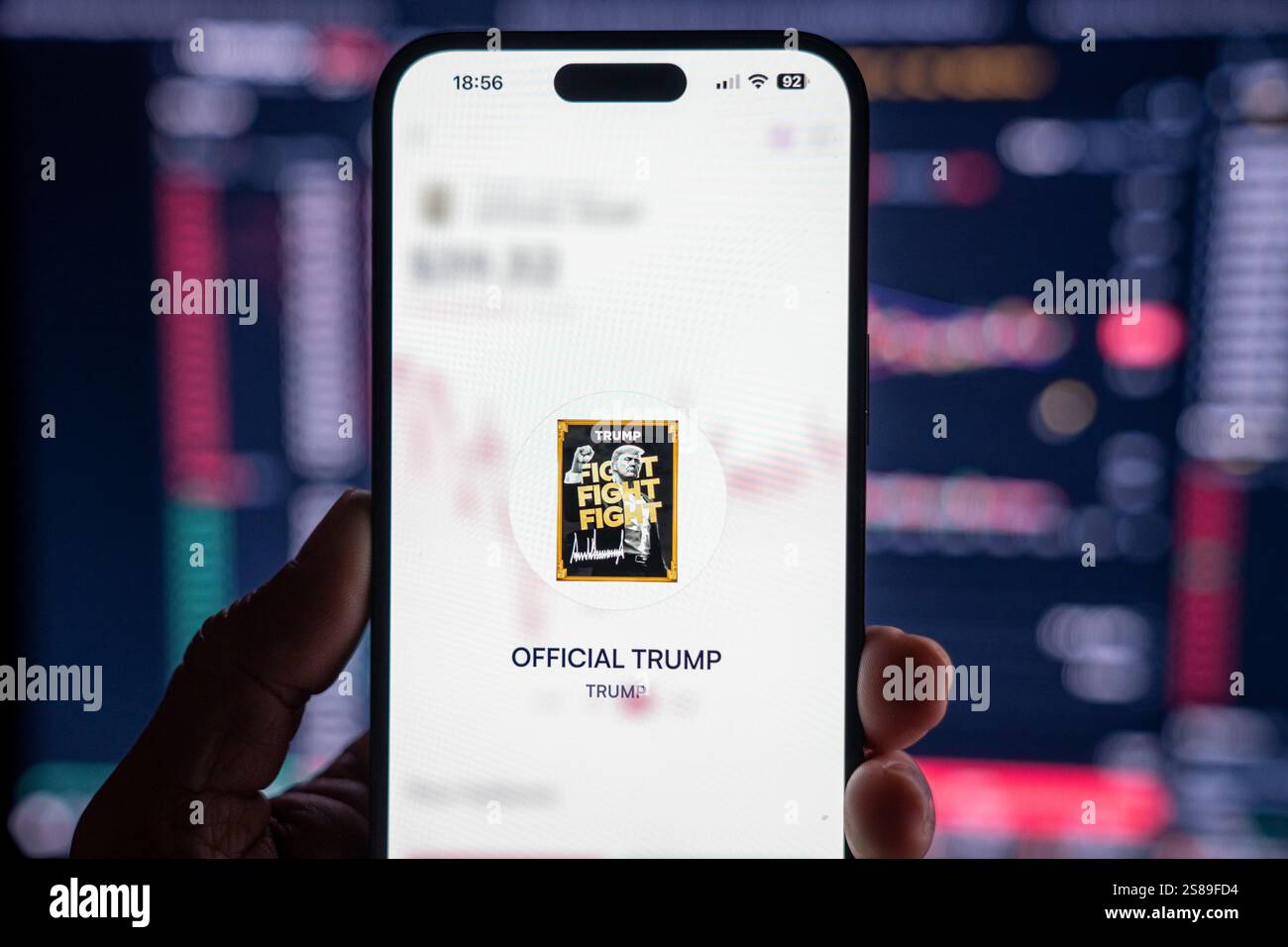 Man holding a phone displaying the OFFICIAL TRUMP meme, with a blurred ...
