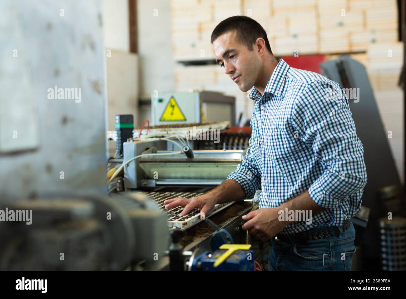 Farmer man working with automatic filling and seeding line for growing ...