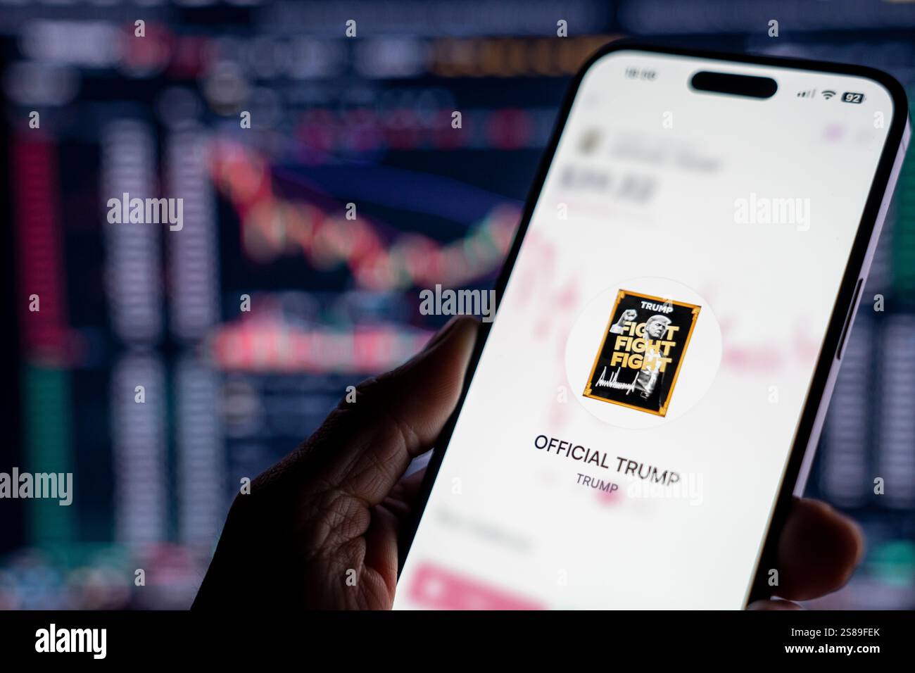 Man holding a phone displaying the OFFICIAL TRUMP meme, with a blurred ...