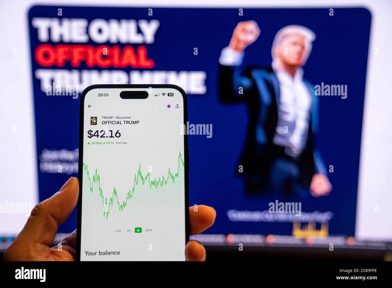 Man holding a phone displaying the official Trump meme logo in the ...