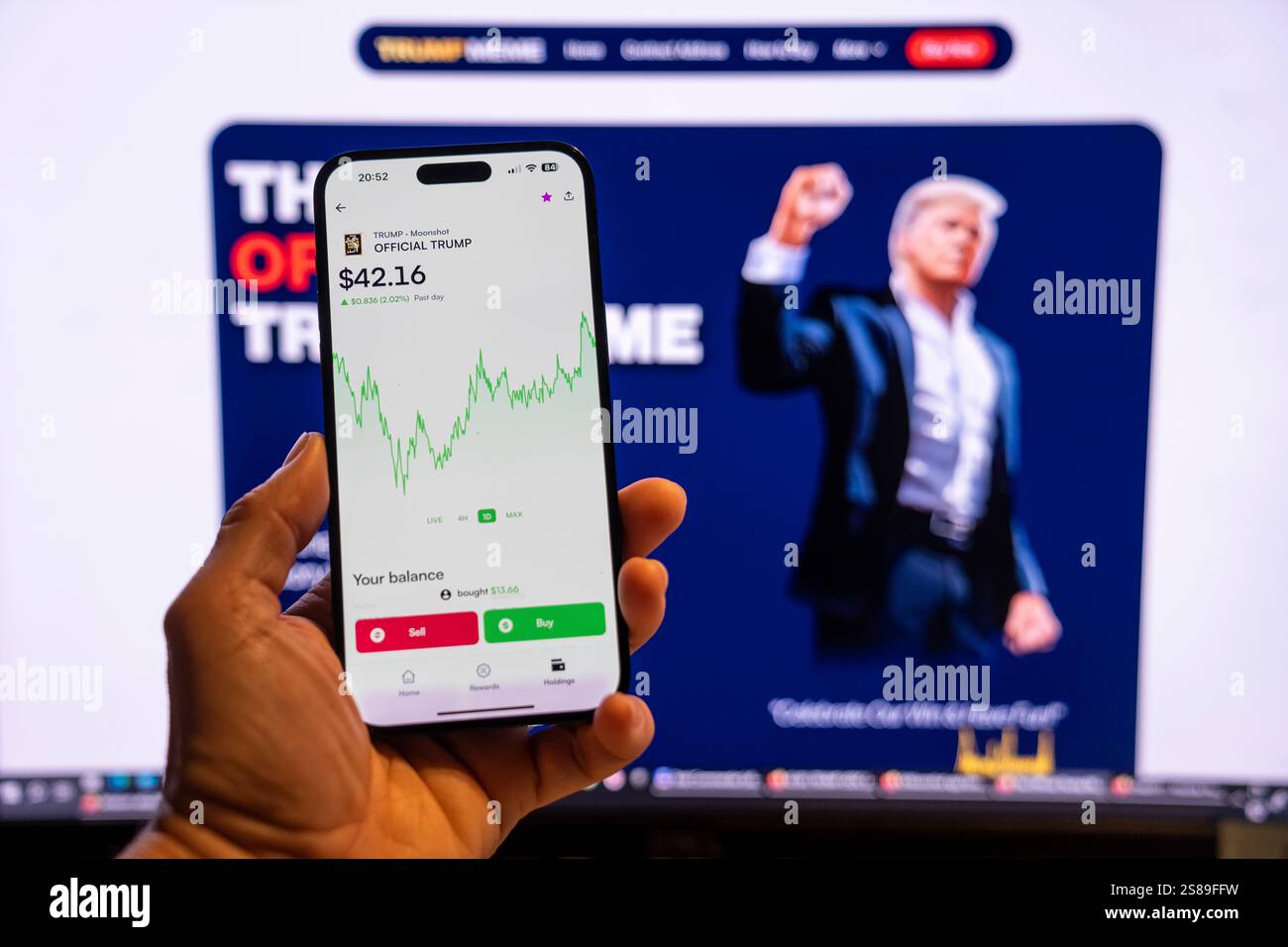 Man holding a phone displaying the official Trump meme logo in the ...