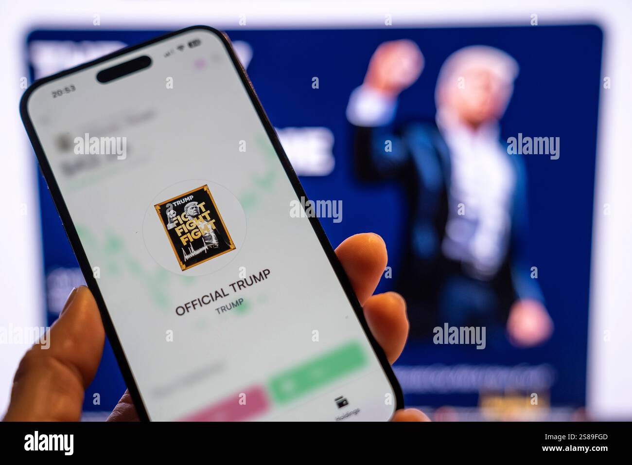 Man holding a phone displaying the official Trump meme logo in the ...