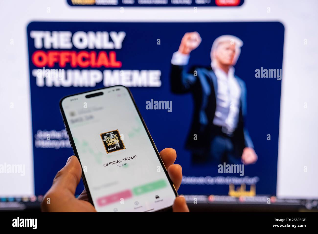Man holding a phone displaying the official Trump meme logo in the ...