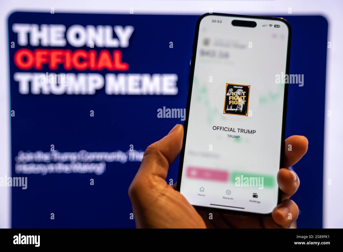 Man holding a phone displaying the official Trump meme logo in the ...