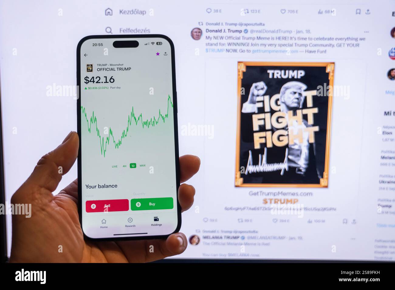 Man holding a phone displaying the official Trump meme logo in the ...
