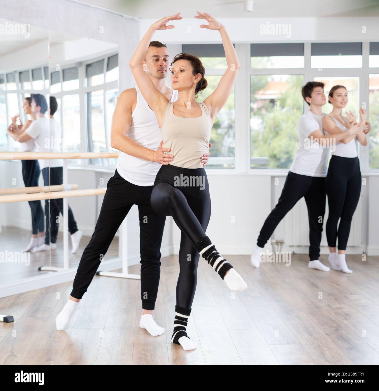 Ballet partners mastering paired technique at group class in studio ...