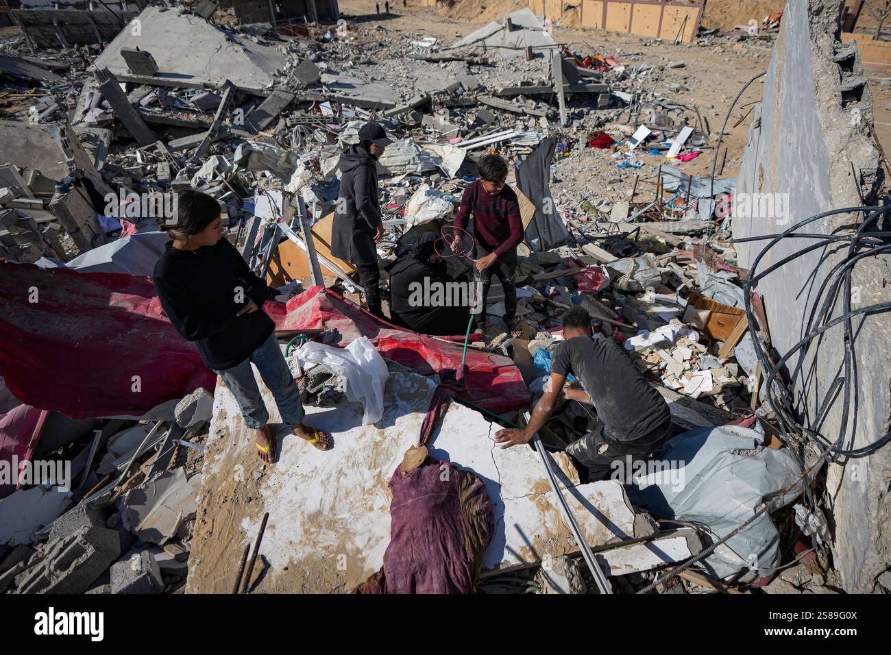 Members of the Abu Al Zamar family salvage items from under the rubble ...