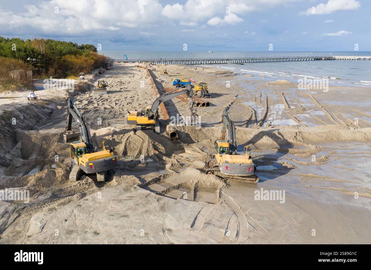 Beach restoration sand Bulldozers. Mud flows from the pipe with ...