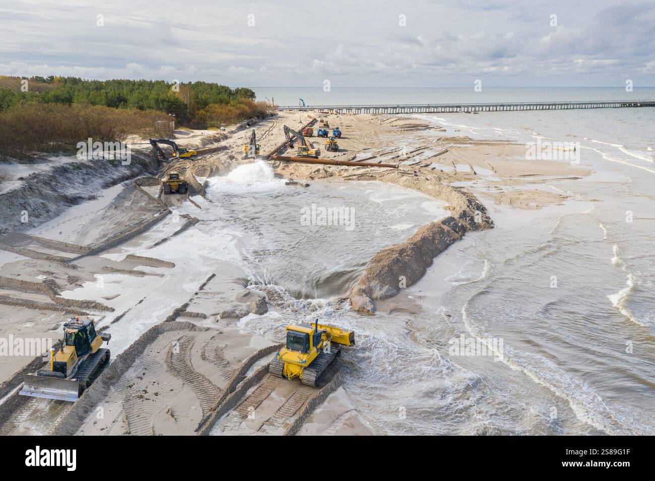 Beach restoration sand Bulldozers. Mud flows from the pipe with ...