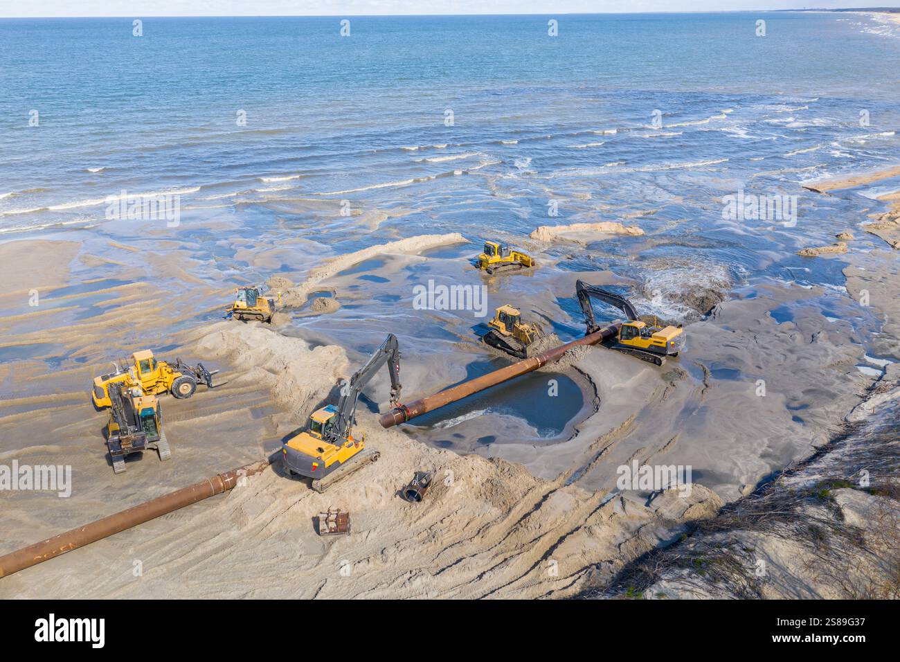Beach restoration sand Bulldozers. Mud flows from the pipe with ...