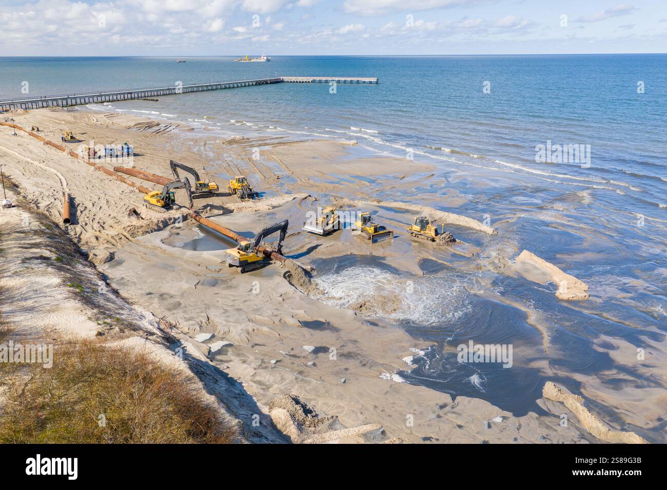 Beach restoration sand Bulldozers. Mud flows from the pipe with ...