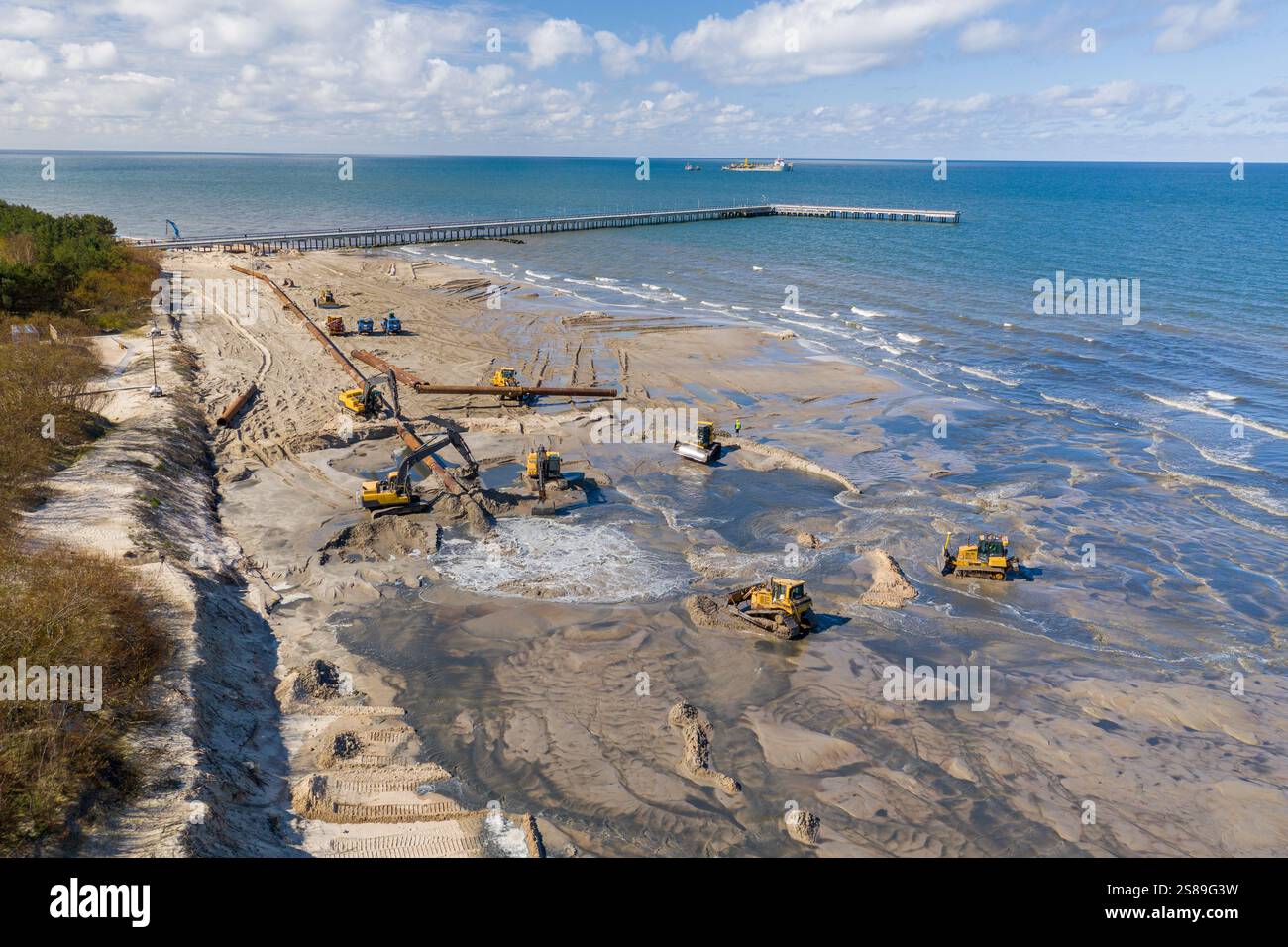 Beach restoration sand Bulldozers. Mud flows from the pipe with ...
