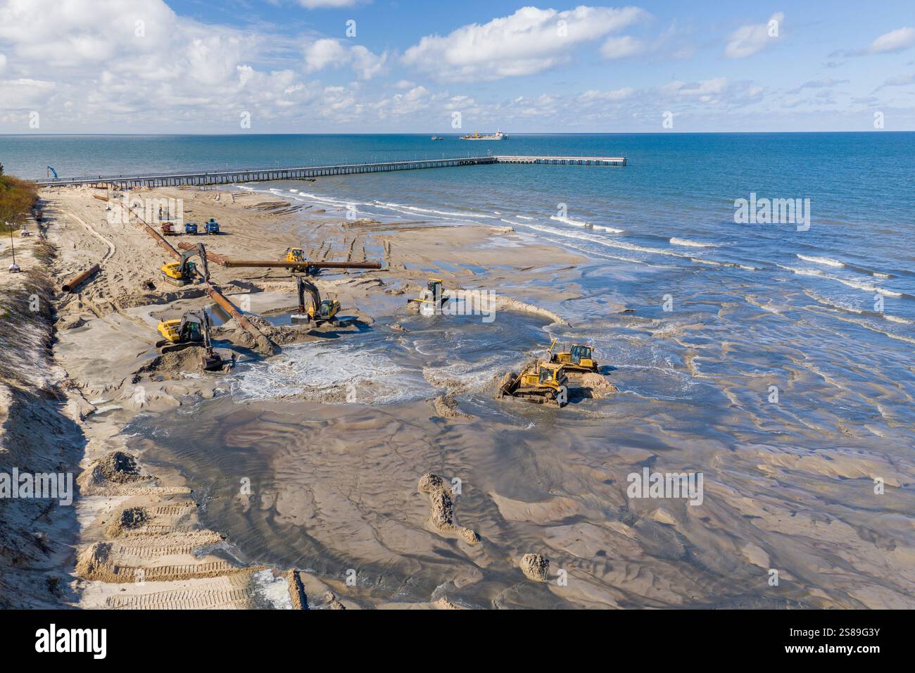 Beach restoration sand Bulldozers. Mud flows from the pipe with ...