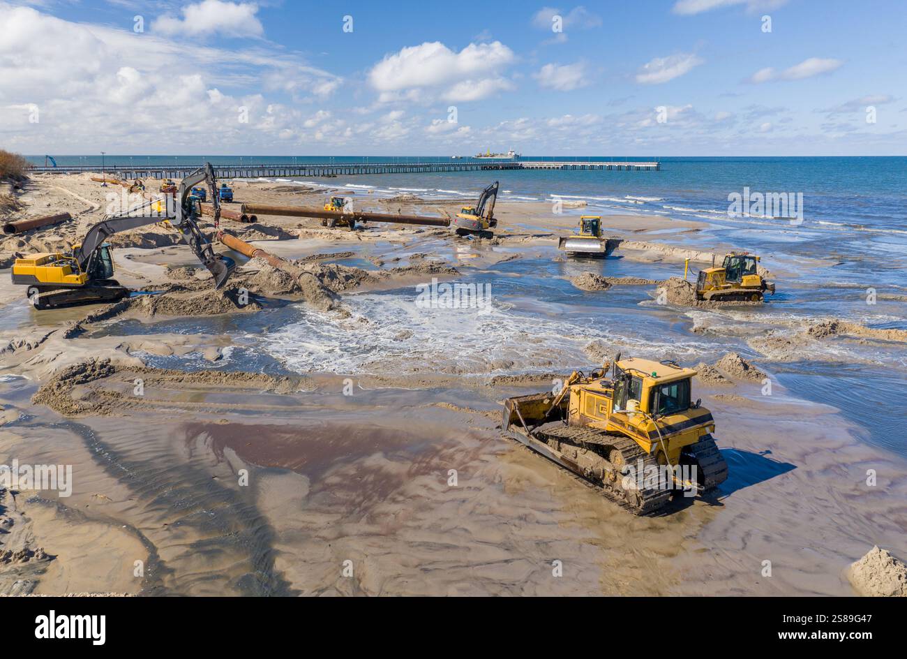 Beach restoration sand Bulldozers. Mud flows from the pipe with ...