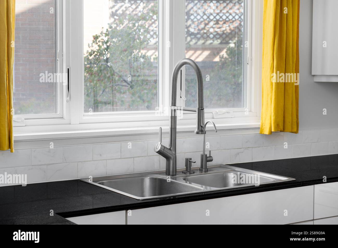 A modern kitchen features a double basin stainless steel sink with a ...