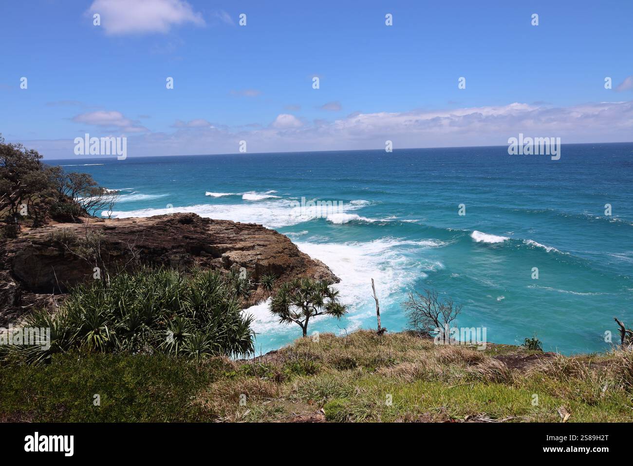 wide-angle blue ocean waves breaking on rocky outcrop shore Stock Photo ...