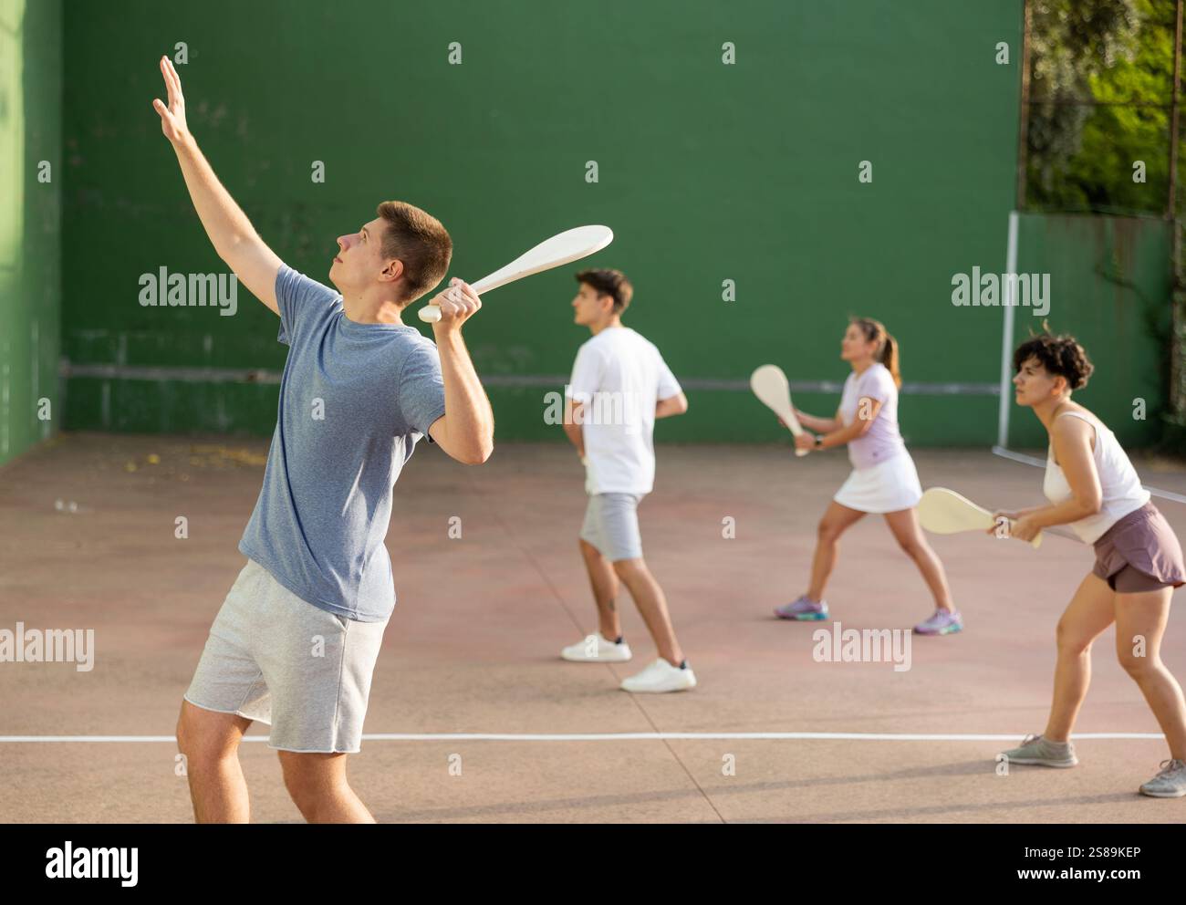 Concentrated young man paleta fronton player hitting ball with racket ...