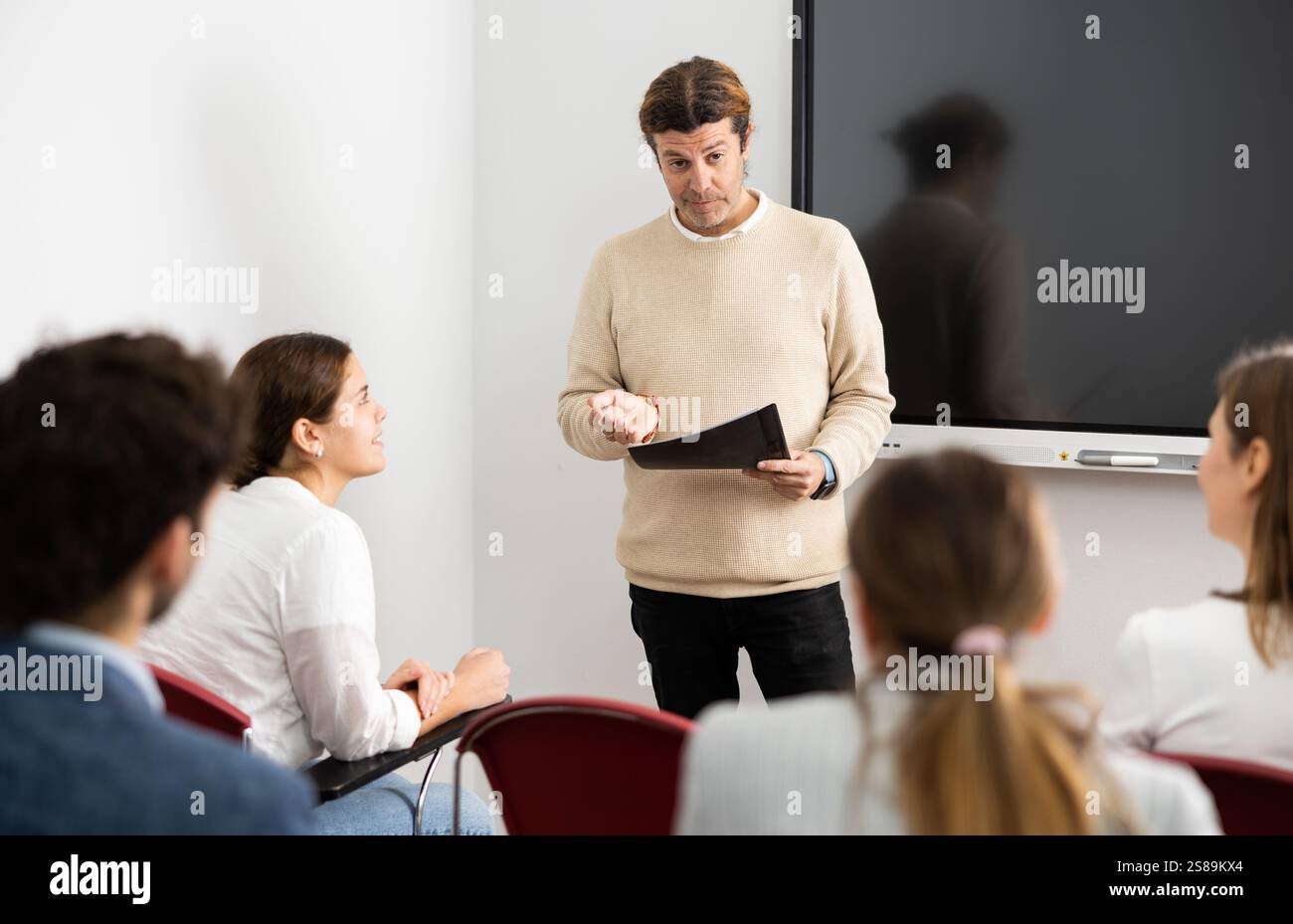 Confident male leader, trainer near interactive board talking to group ...