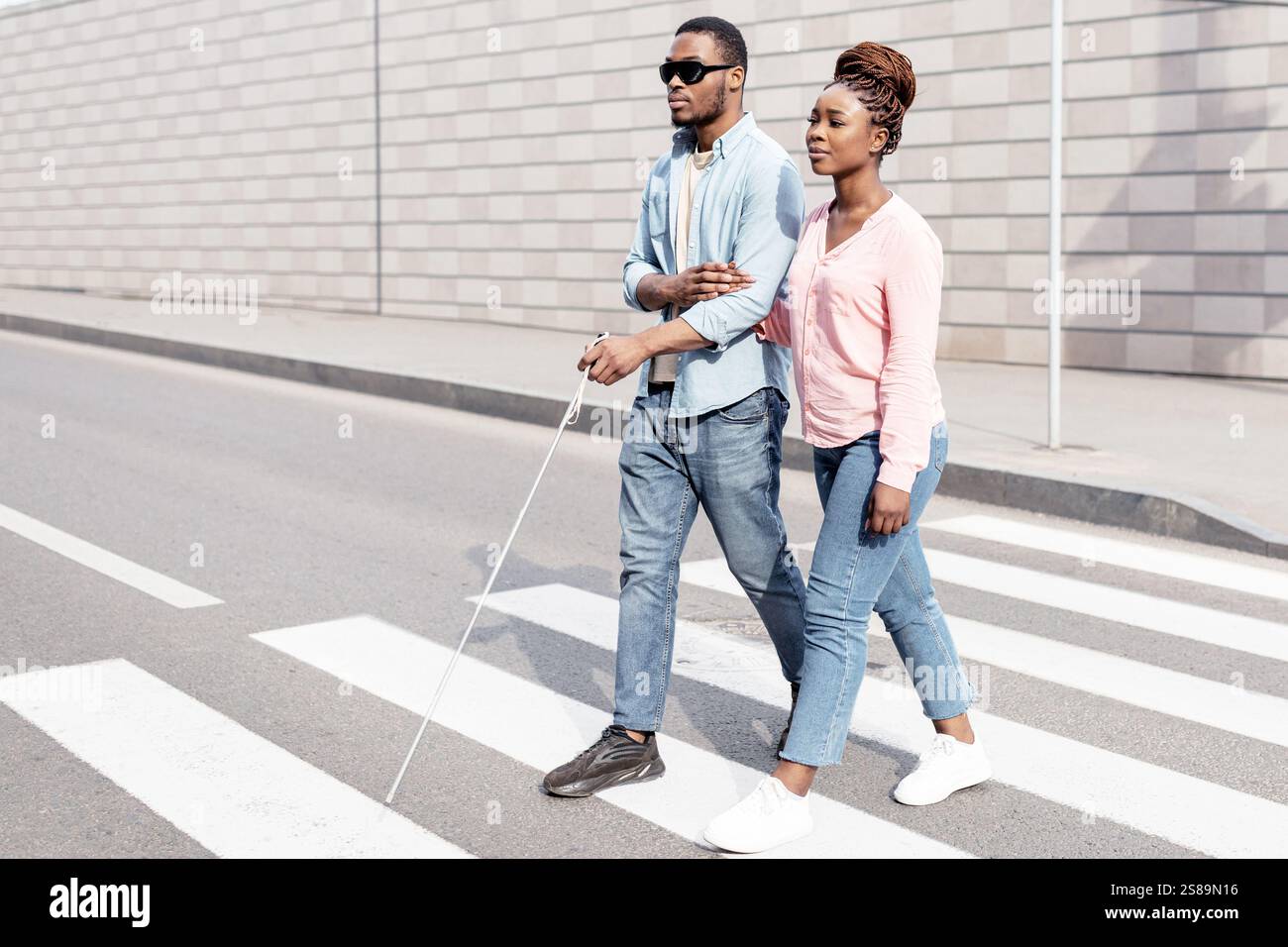 Young black woman assisting visually impaired millennial guy with cane ...