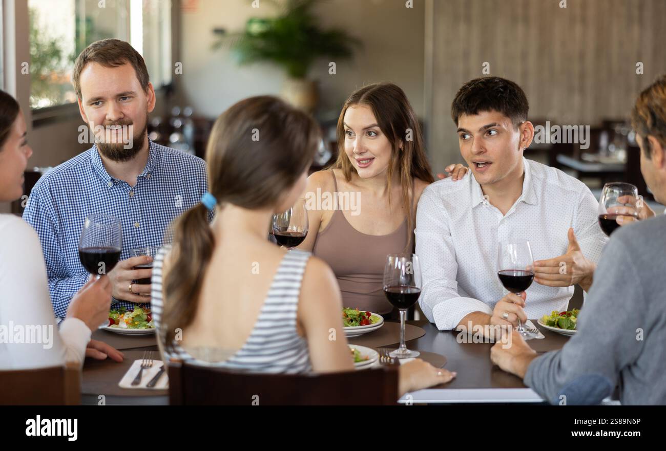 Group of friends talking and eating in restaurant Stock Photo - Alamy