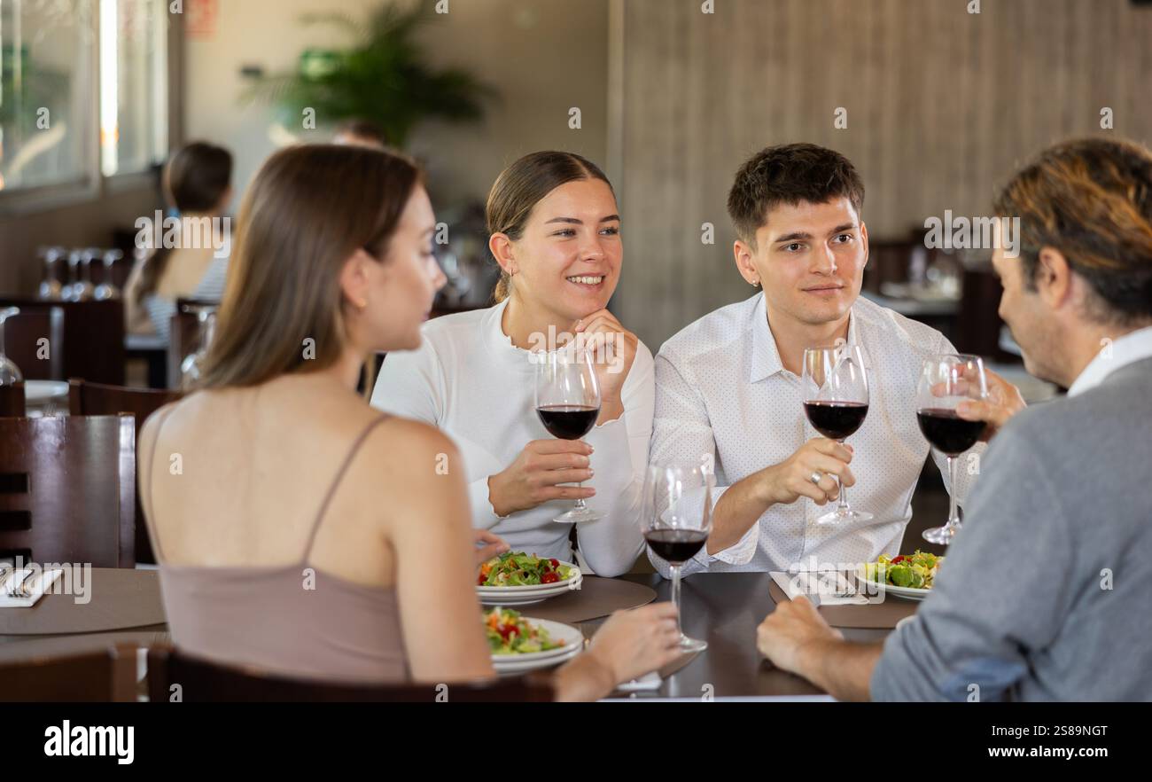 Couples of men and women talking and eating in restaurant Stock Photo ...