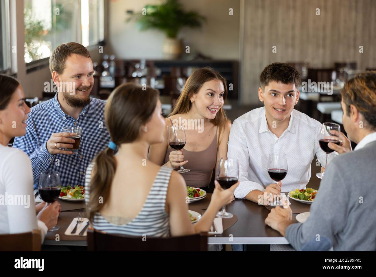 Group of friends talking and eating in restaurant Stock Photo - Alamy