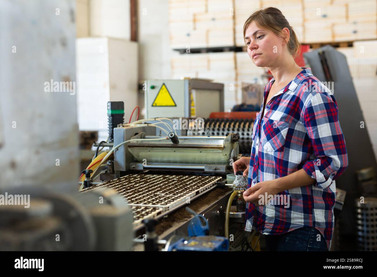 Confident woman machine operator working with automatic conveyor ...