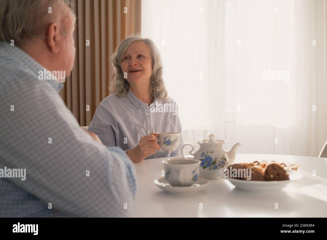 Elderly couple enjoying tea time together in a cozy and bright setting ...