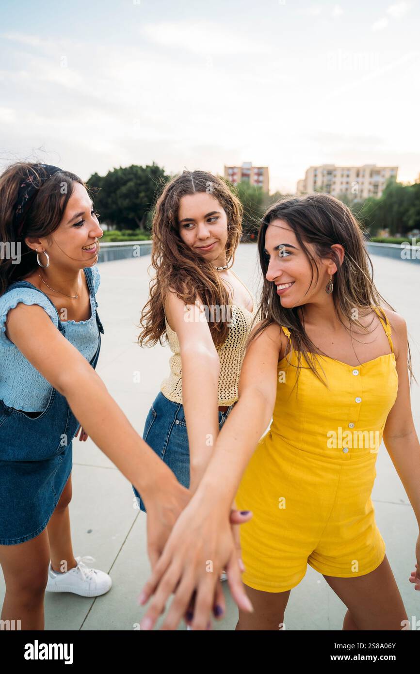 Three young women joining hands in friendship and teamwork outdoors Stock Photo - Alamy
