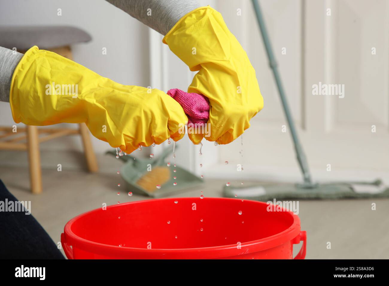 A woman in yellow gloves squeezing the cloth over a bucket Stock Photo ...