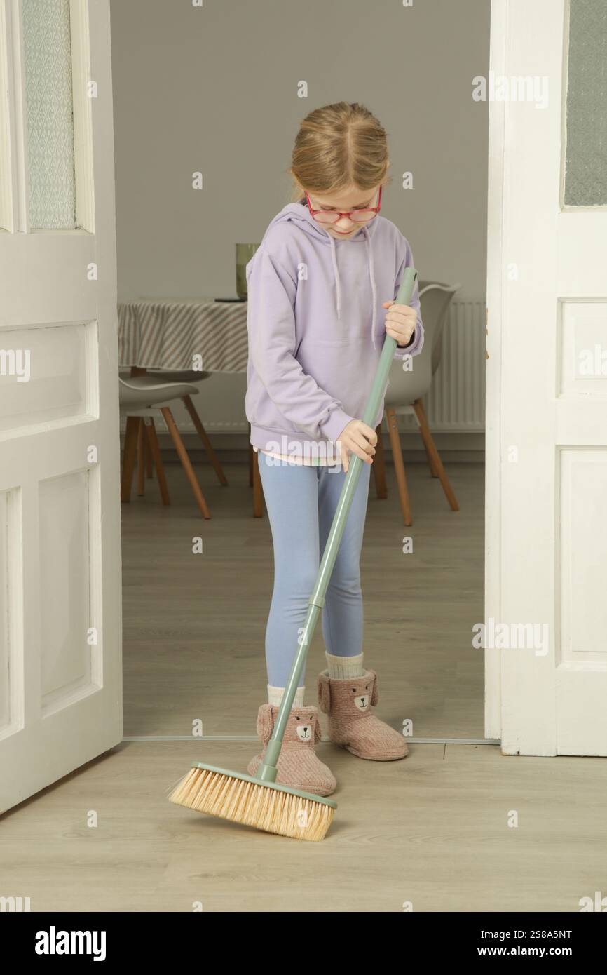 Child sweeping floor with broom. Including chores in a child's routine ...