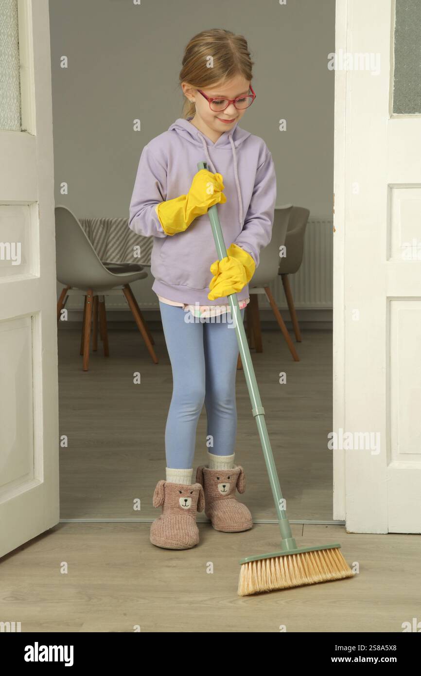 Child sweeping floor with broom. Including chores in a child's routine ...