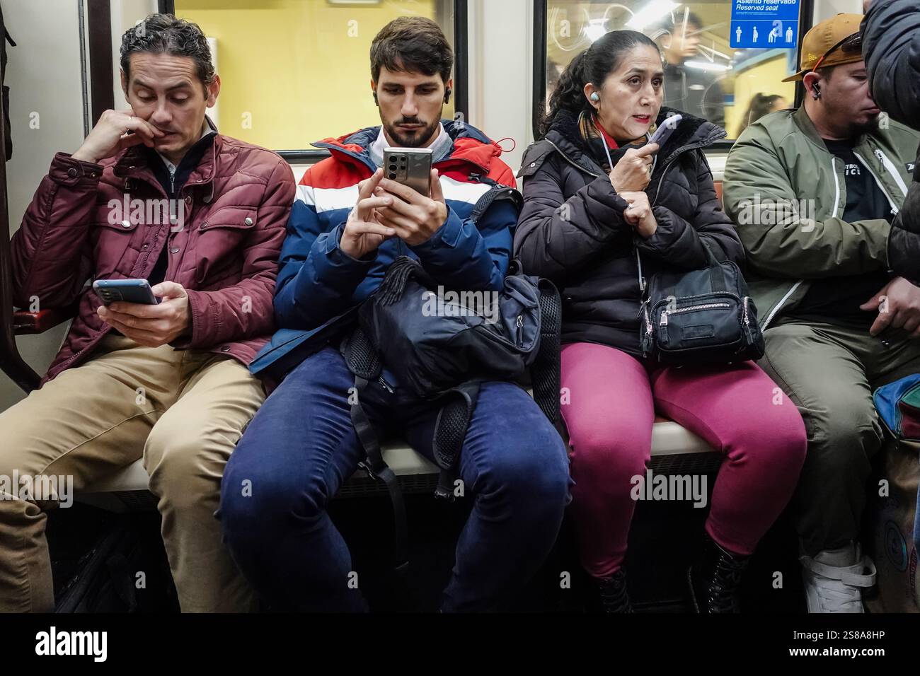 A group of Spanish people sitting tightly on a subway train in Madrid ...