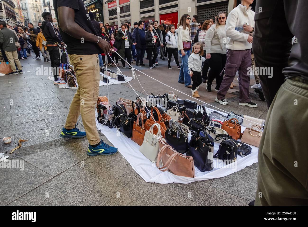 Illegal street vendor selling fake goods in a bustling street in Madrid ...
