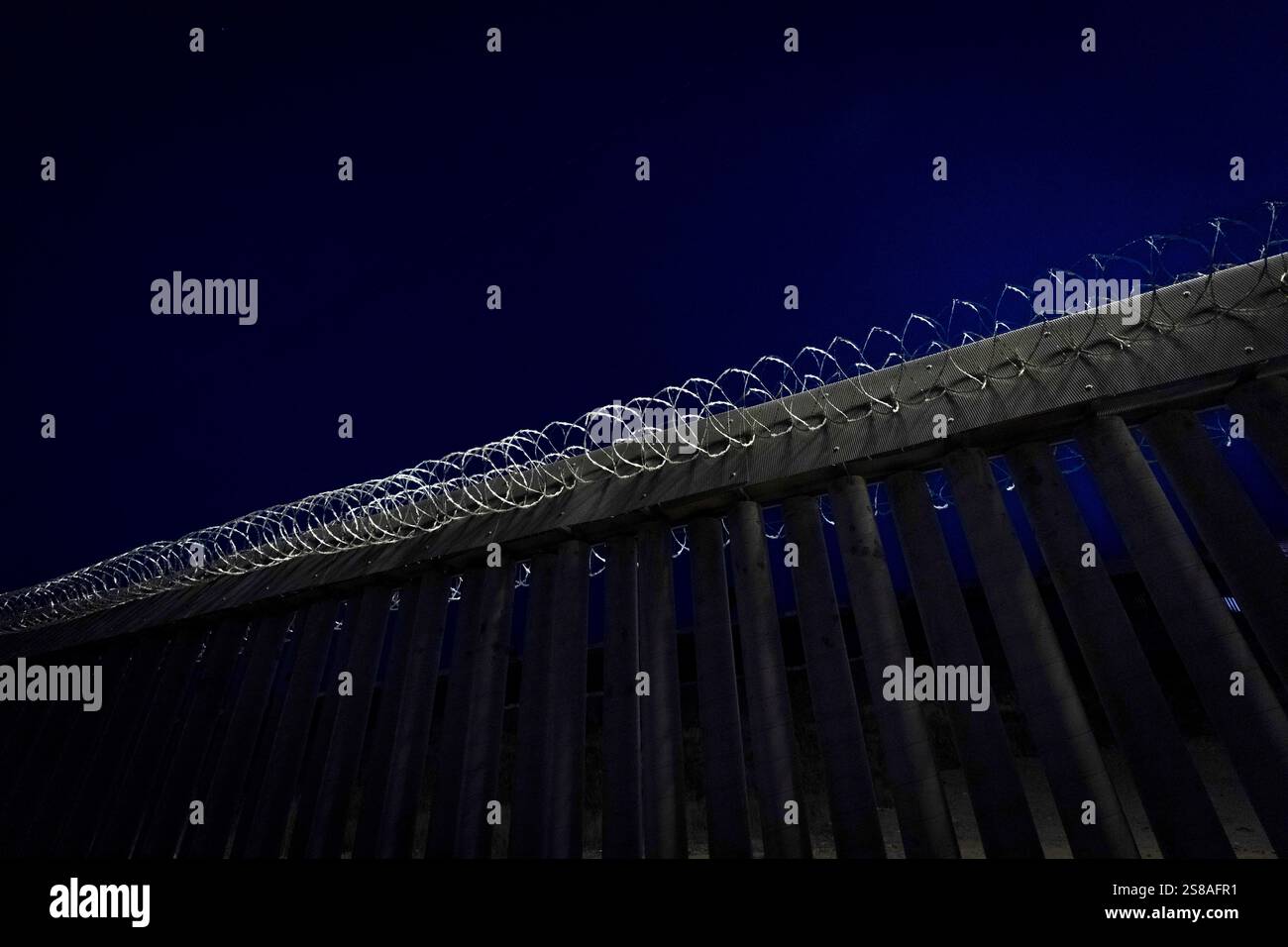 Concertina wire tops a section of a border wall separating Mexico from ...