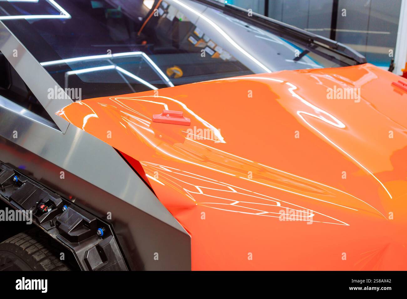Innovative electric vehicle worker applies vibrant orange vinyl film to car for protect body ...