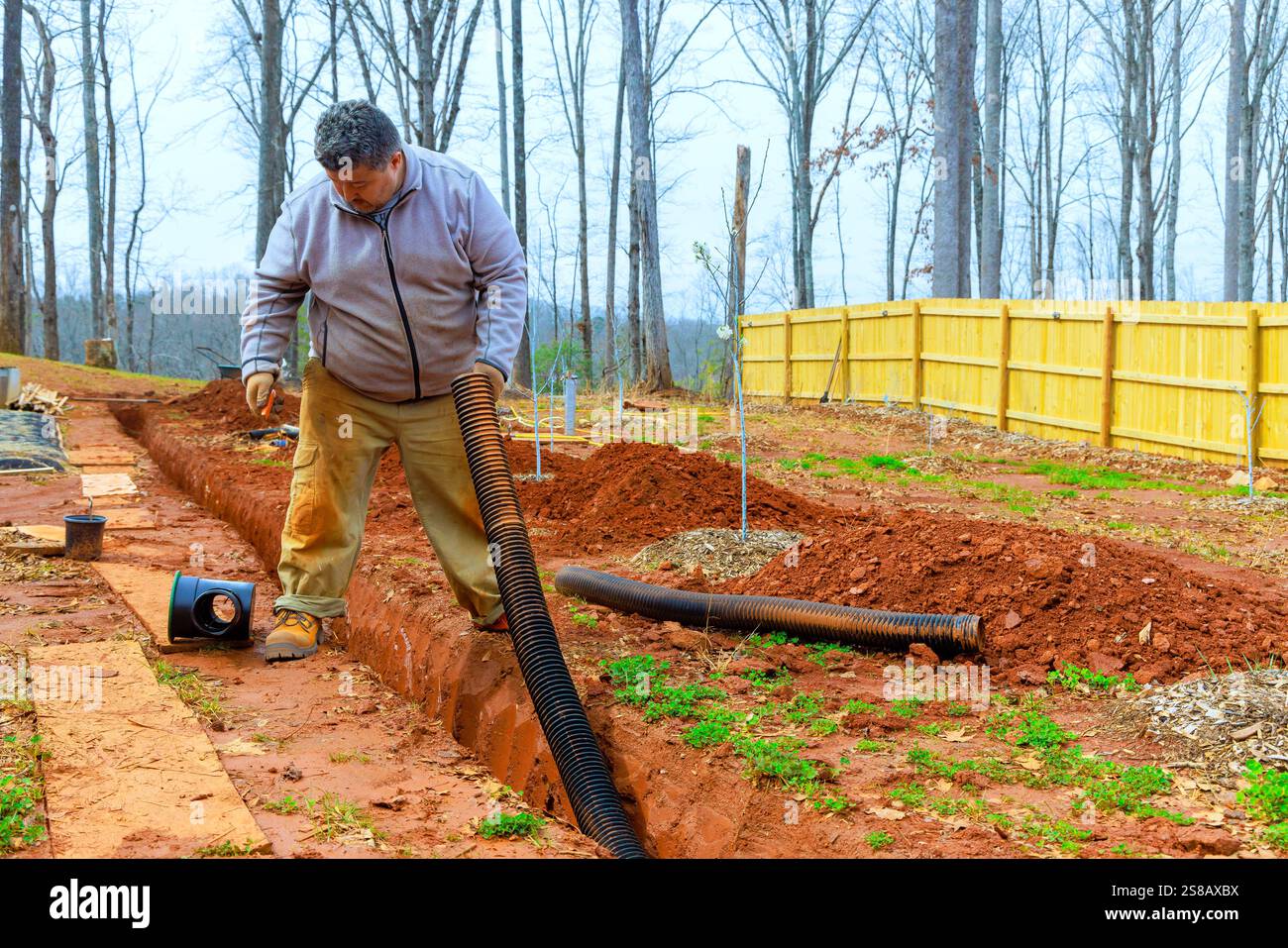 Worker works diligently to install drainage system in his backyard ...