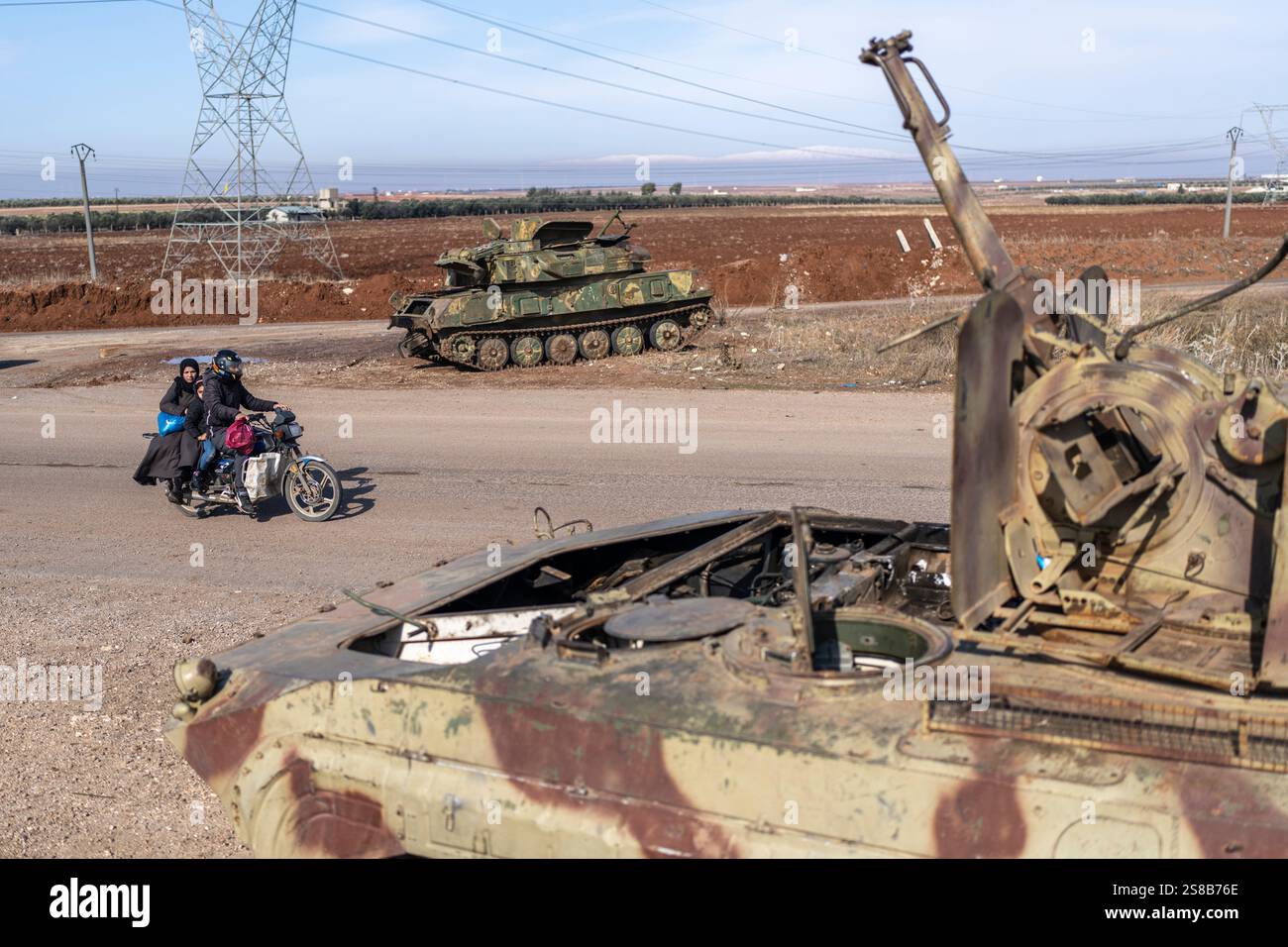 A family drives past tanks that belonged to the Assad government, in ...