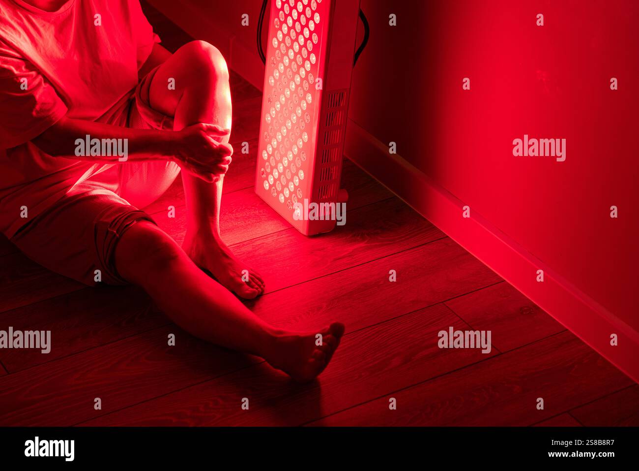 Close-up of an elderly woman sitting near a red light therapy device ...