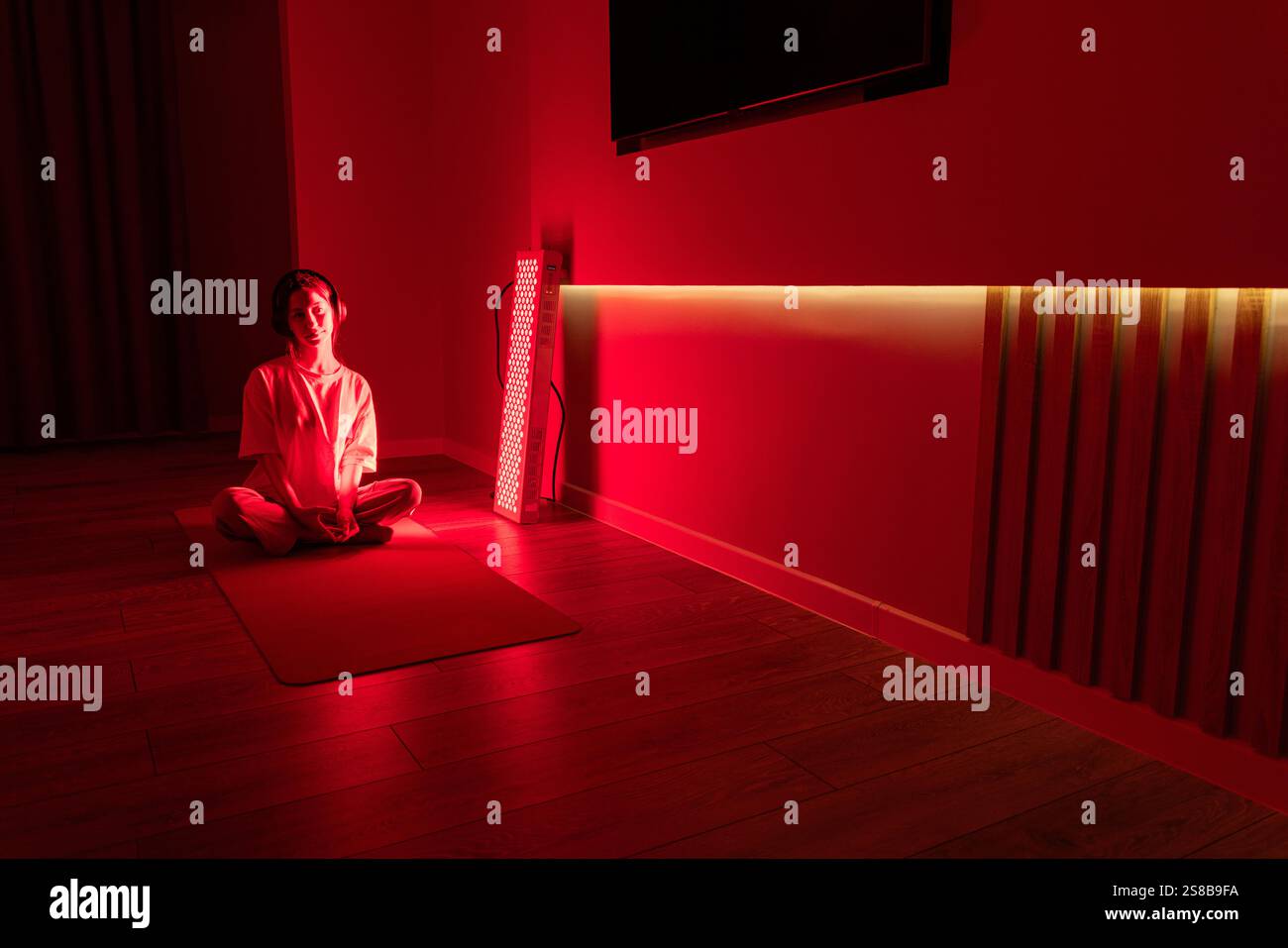 A young woman relaxing on a yoga mat during a red light therapy session ...
