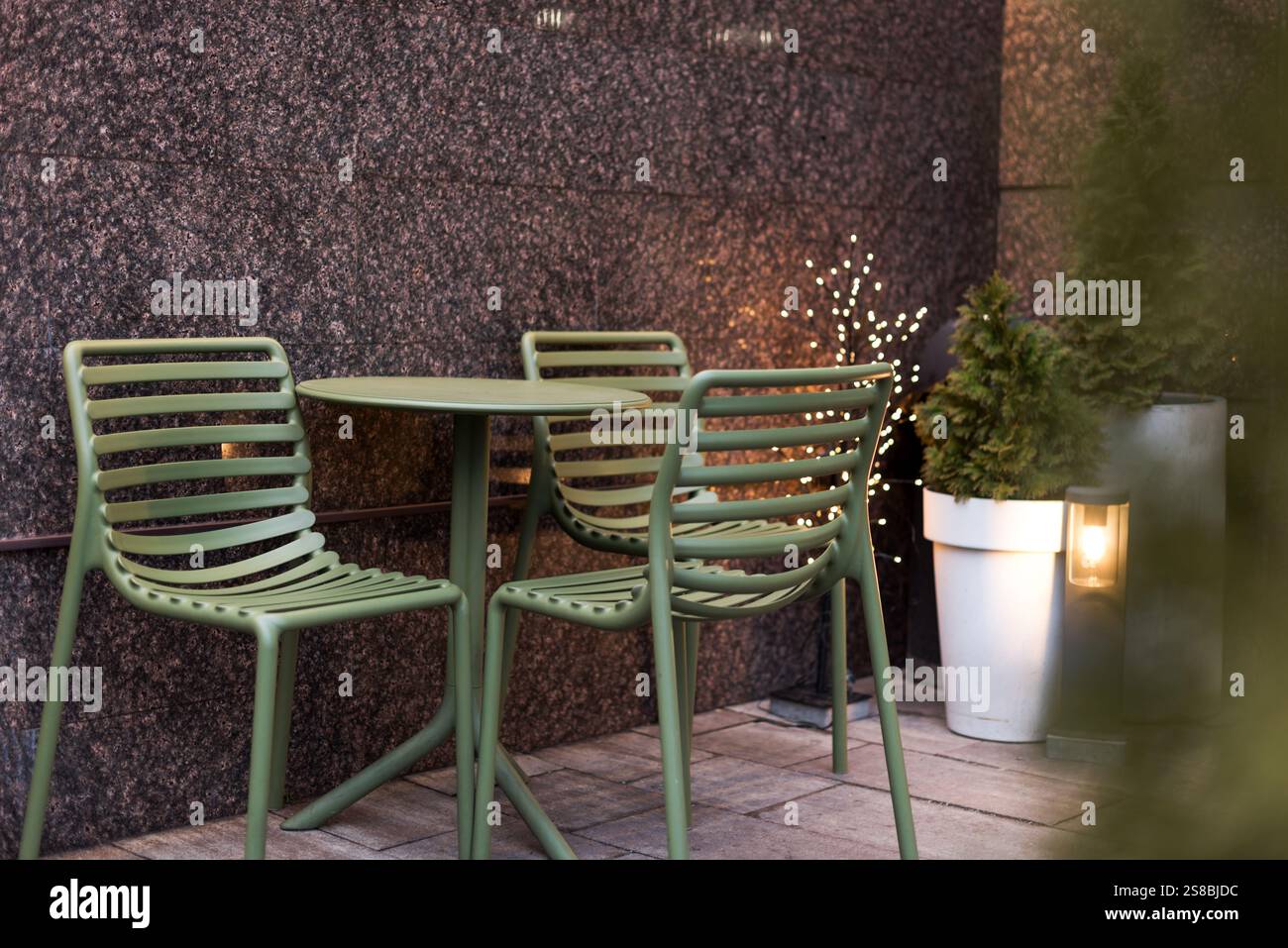An inviting outdoor cafe area featuring green metal furniture, potted ...