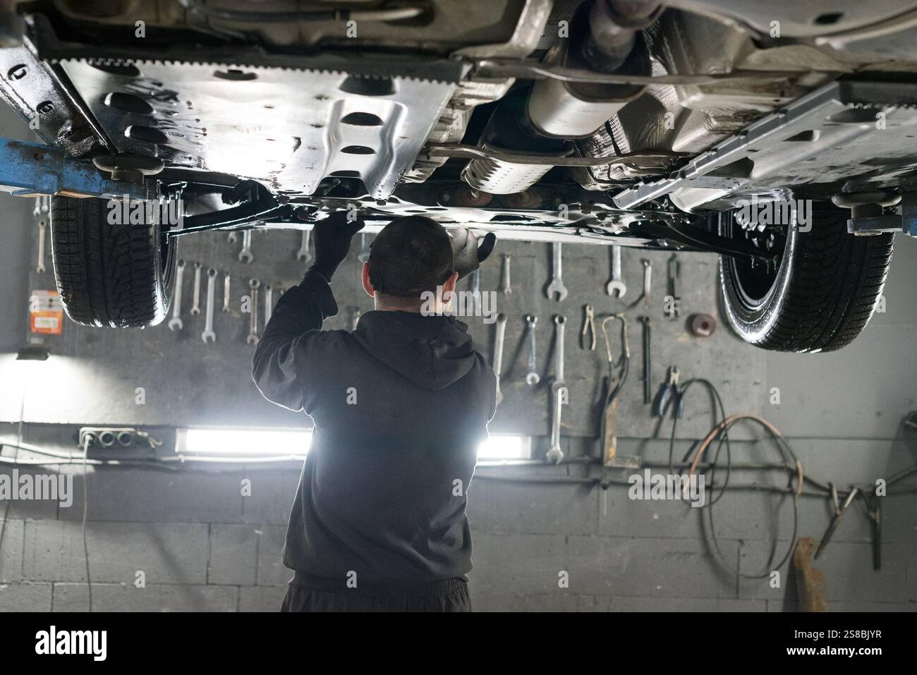 Mechanic Working Beneath a Raised Car in an Automotive Repair Garage ...
