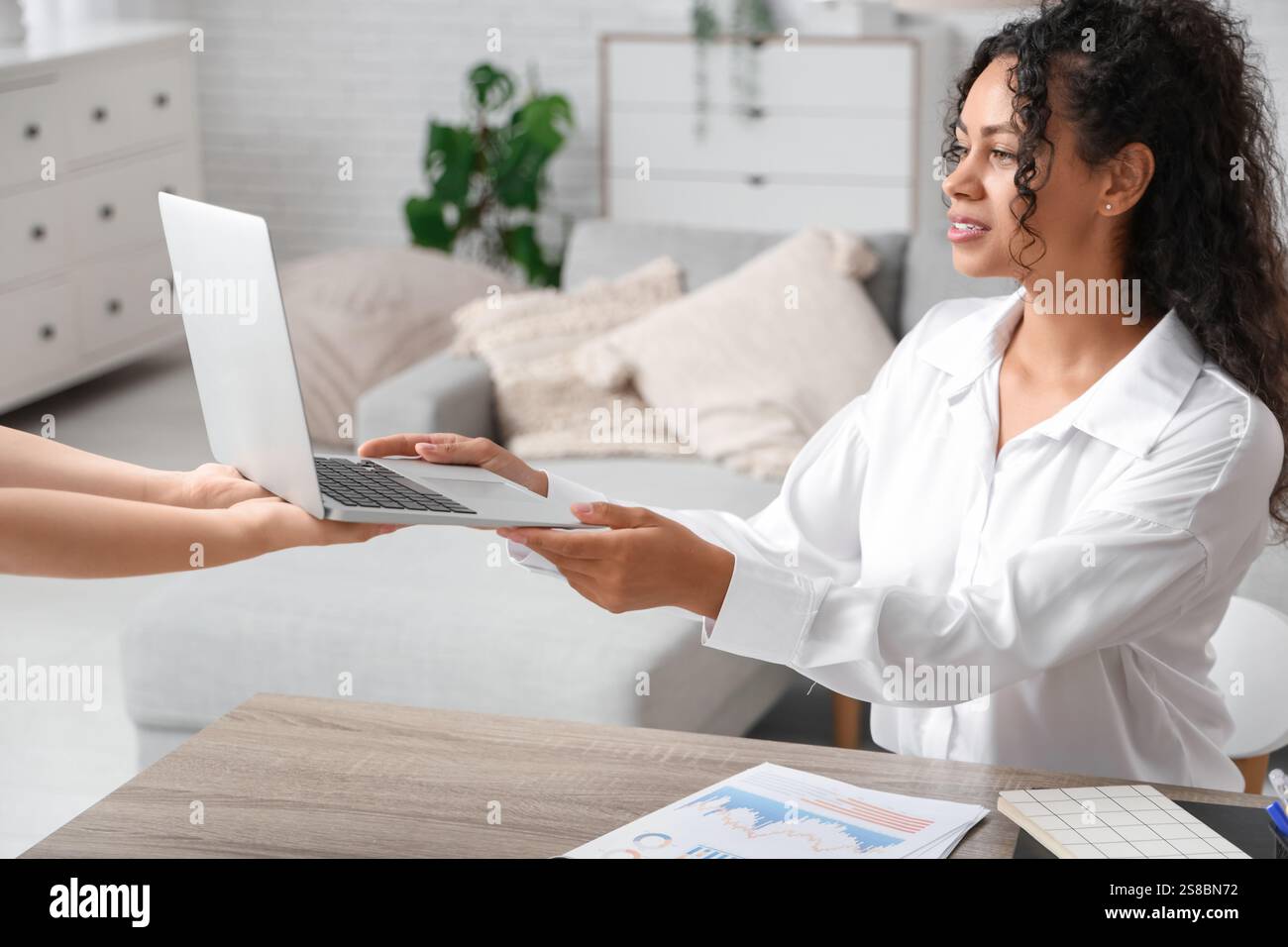 Pretty young African-American woman taking laptop from another person ...